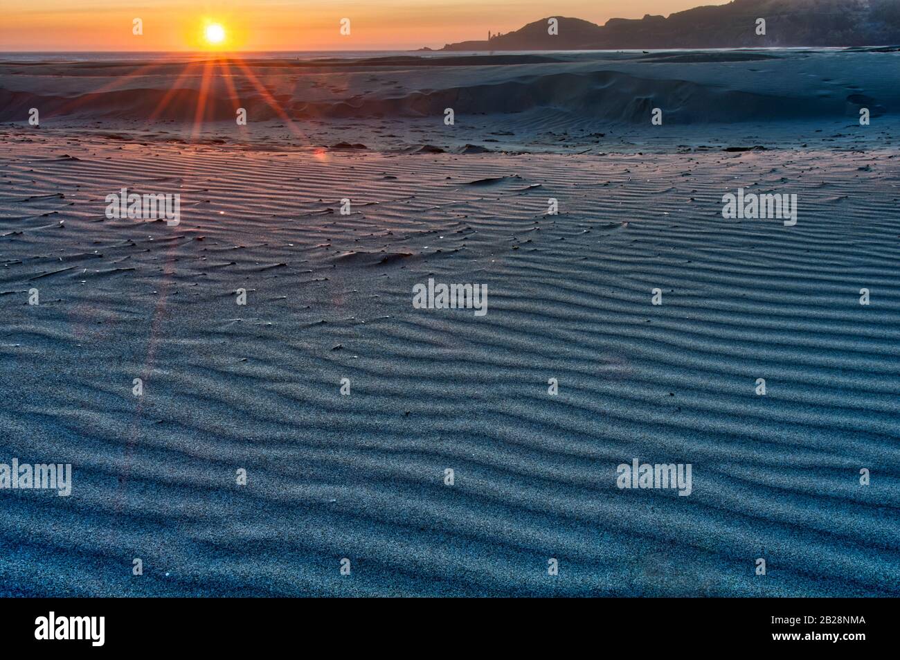 Orange Sun Setting behind the clouds framing the Pacific Ocean horizon ...