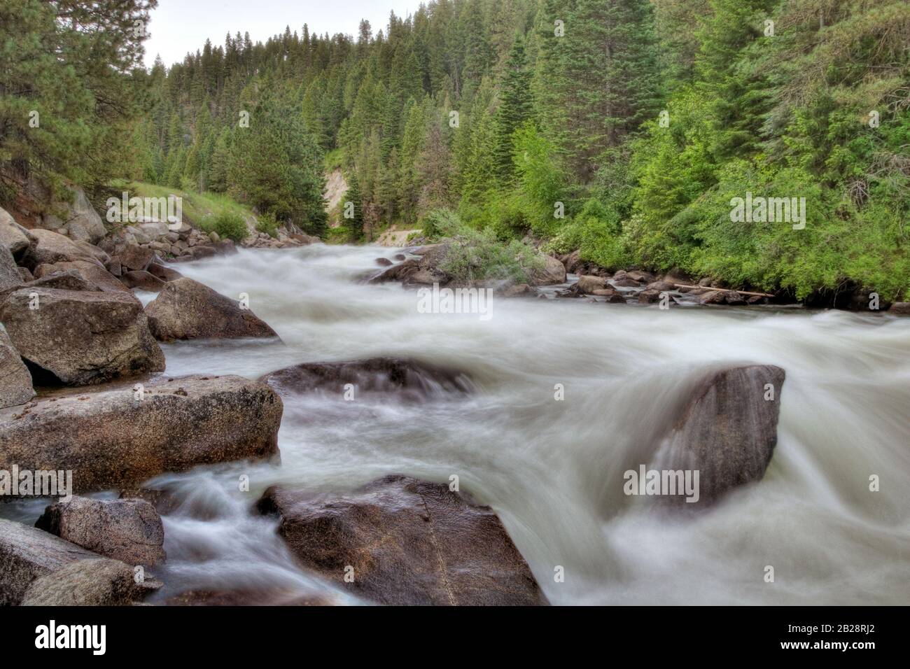 Rushing and flowing river water moving fast and blurred through the ...