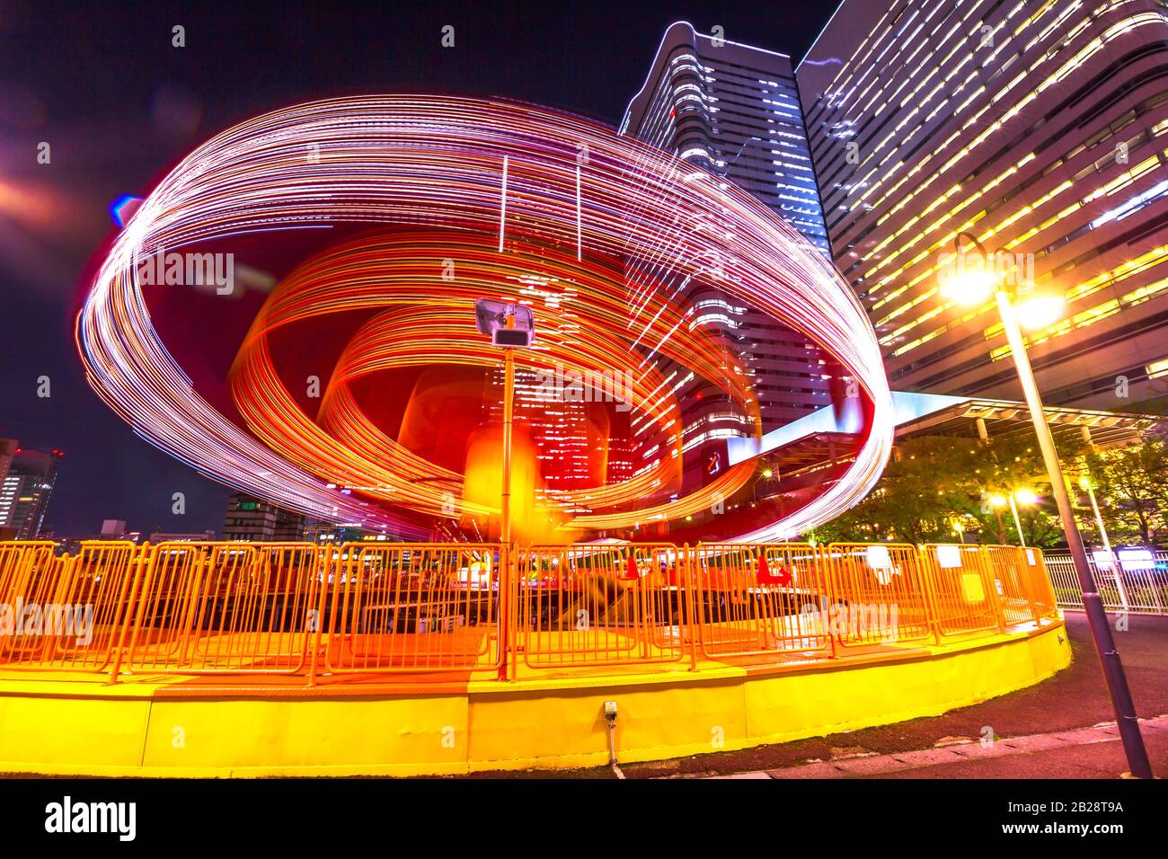 A colorful scenic carousel rotates on itself fast, illuminated at night ...