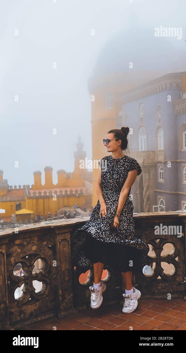 Young woman sitting and enjoying view of Pena Palace in Sintra ...