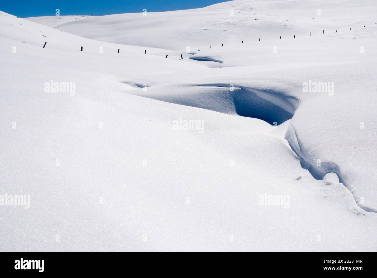 Deep snow drift and snow berm in the fold between two hills with a half ...