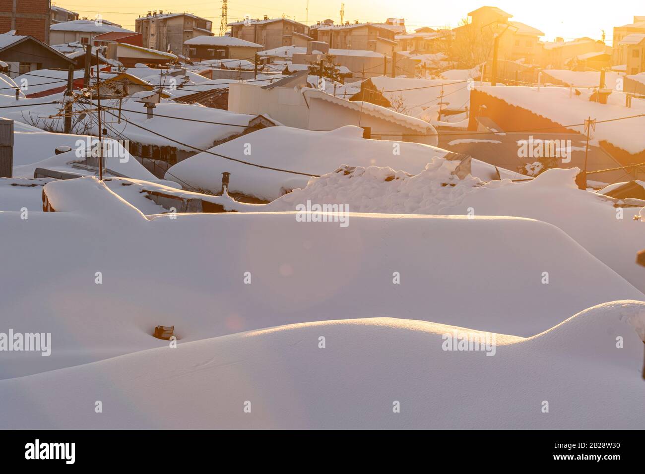 Snow on rooftops in winter season landscape with rising sun at horizon ...