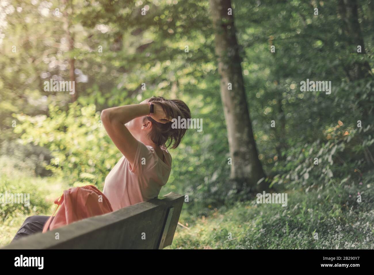 Female hiker resting on the bench in park after trekking through woods ...