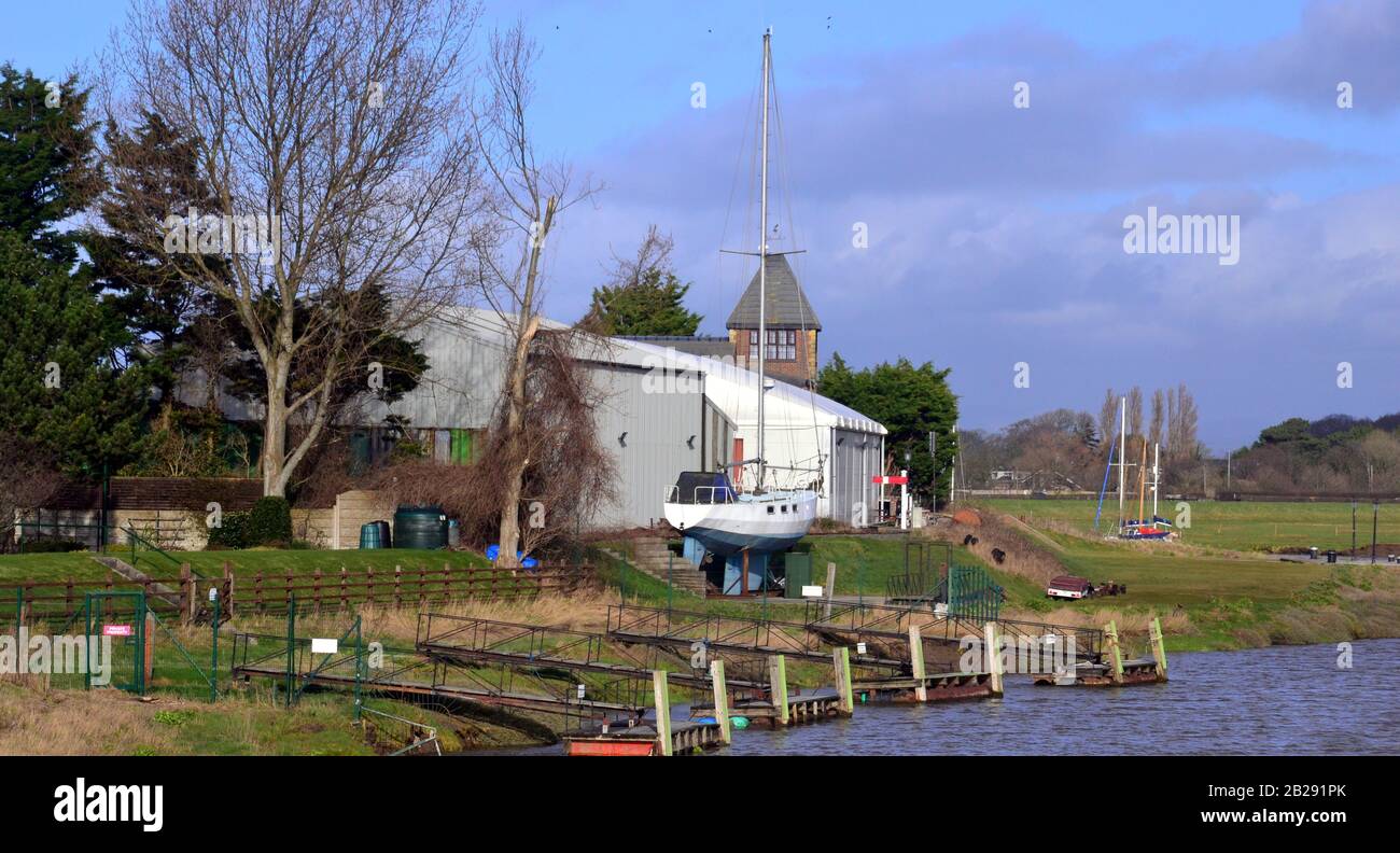 A coastal scene, including a sailing dinghy out of the water, next to ...