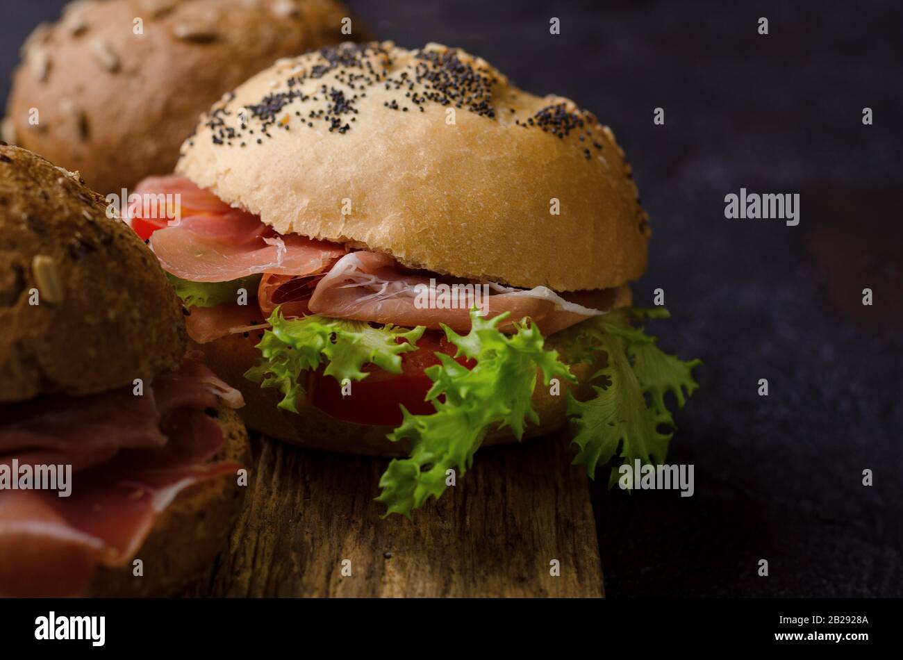 Delicious crispy burger bun with sliced ham on a vintage wooden cutting ...