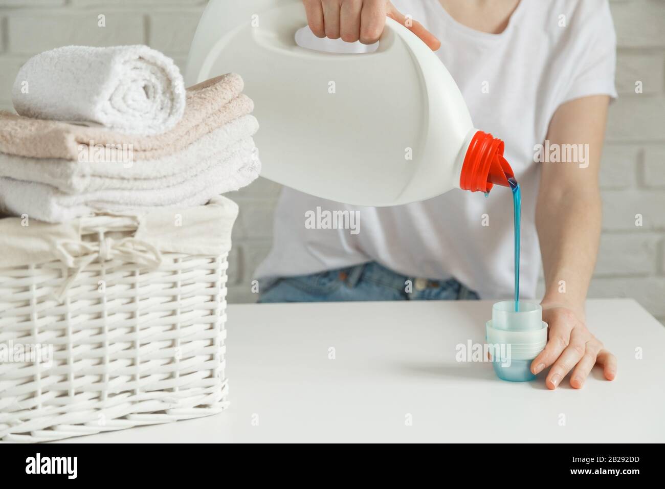 Close up of female hands pouring liquid laundry detergent into cap on ...