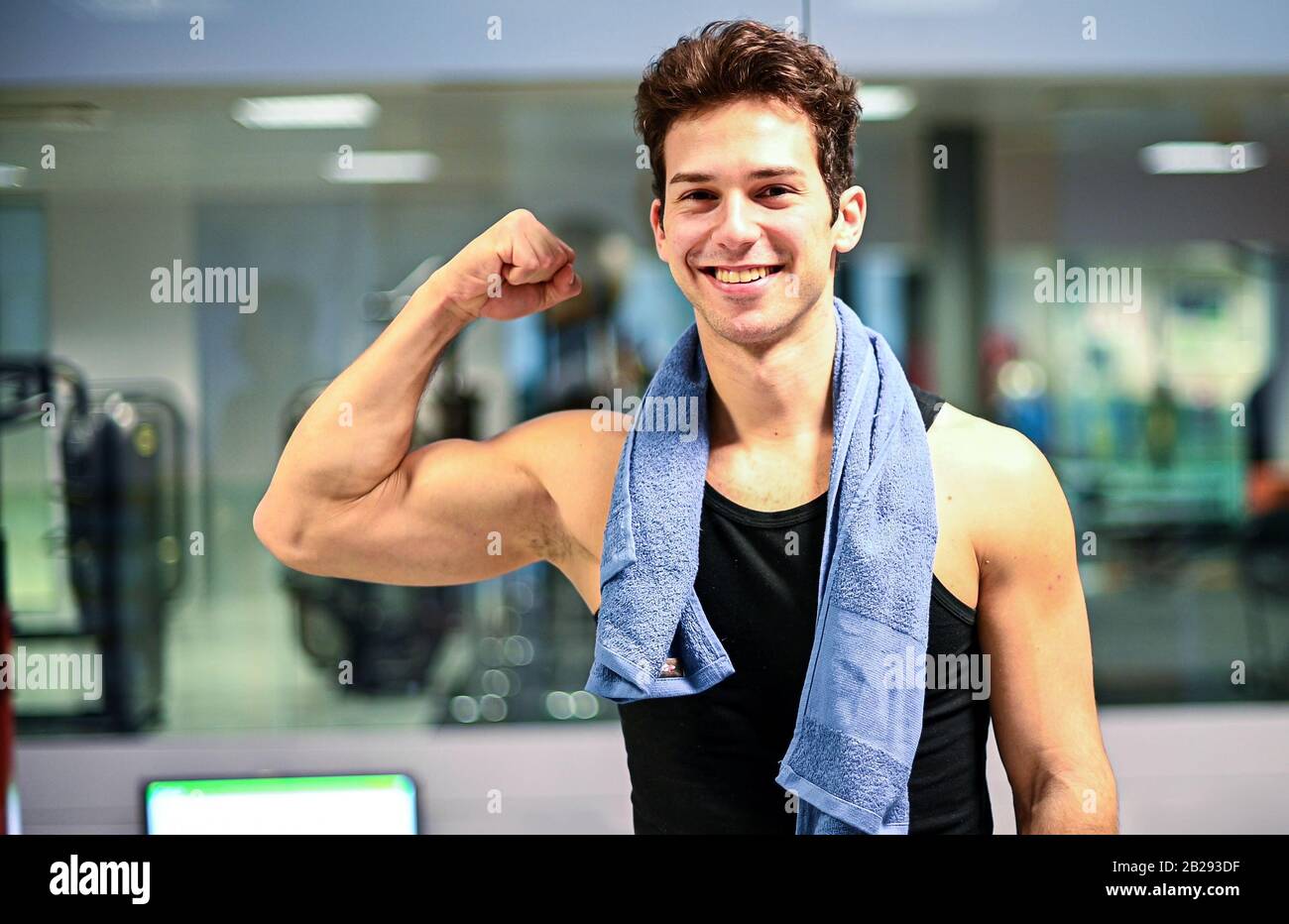 Smiling personal trainer showing his muscle hi-res stock photography ...