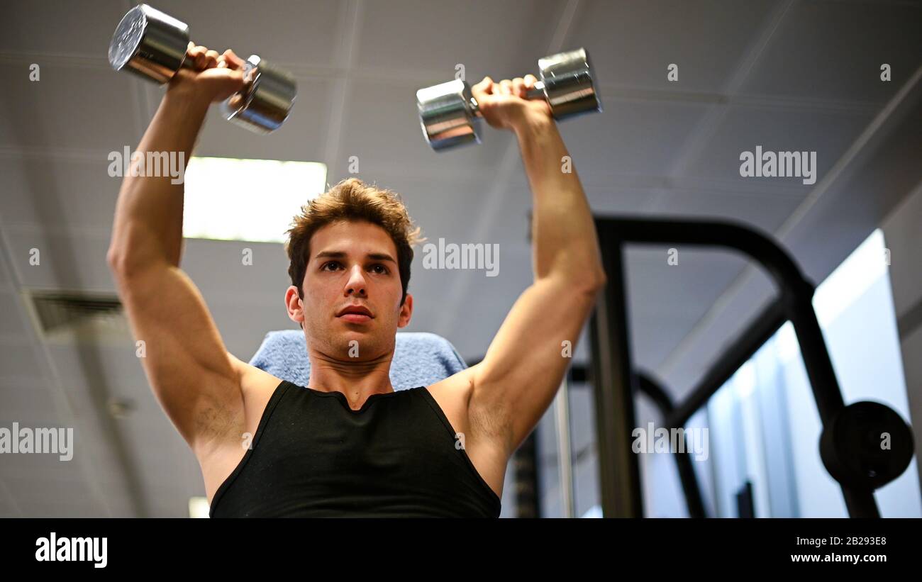 Bodybuilder lifting dumbbells to work out his arms and shoulders in a ...