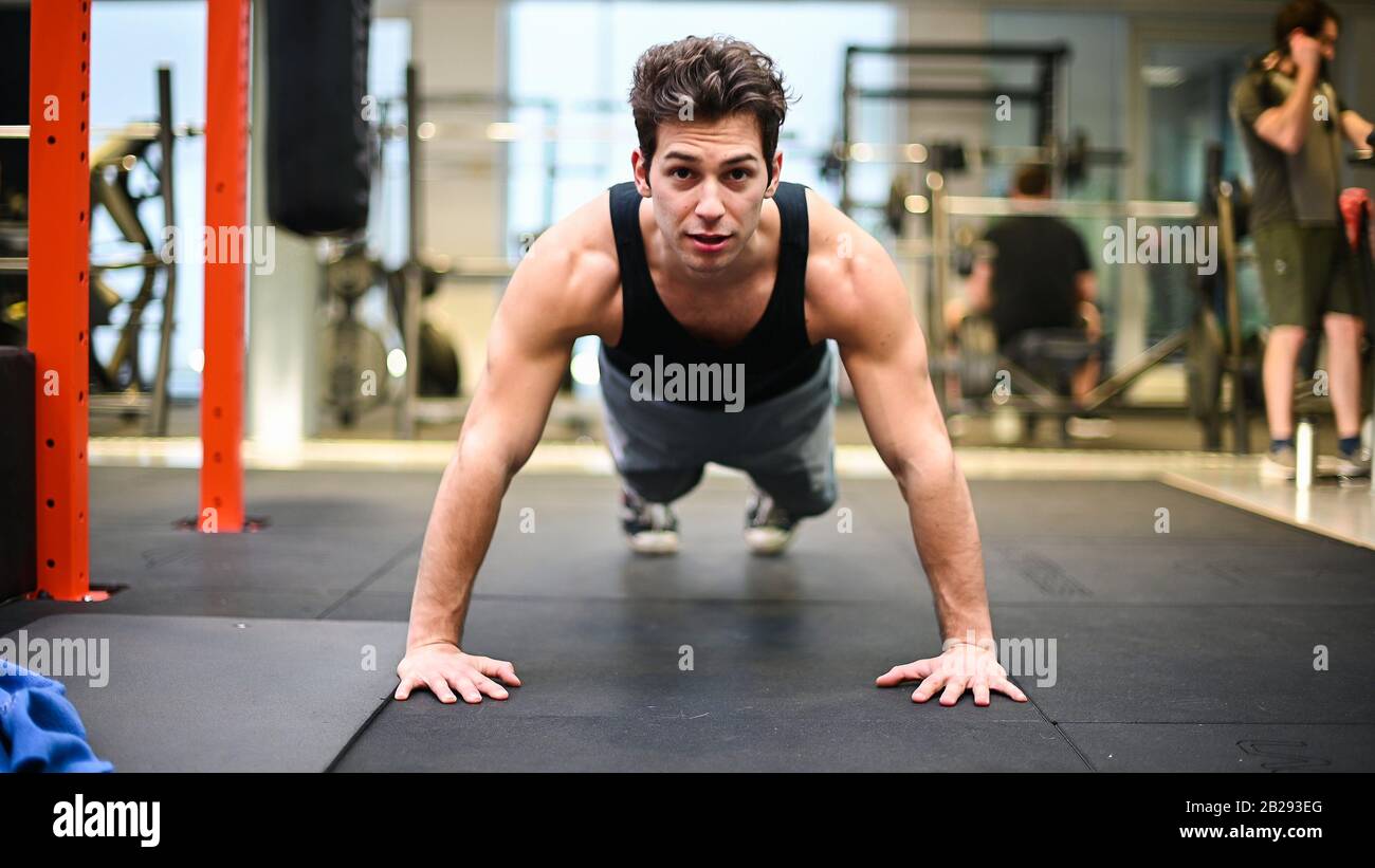 Young fit man doing push ups in a gym Stock Photo - Alamy