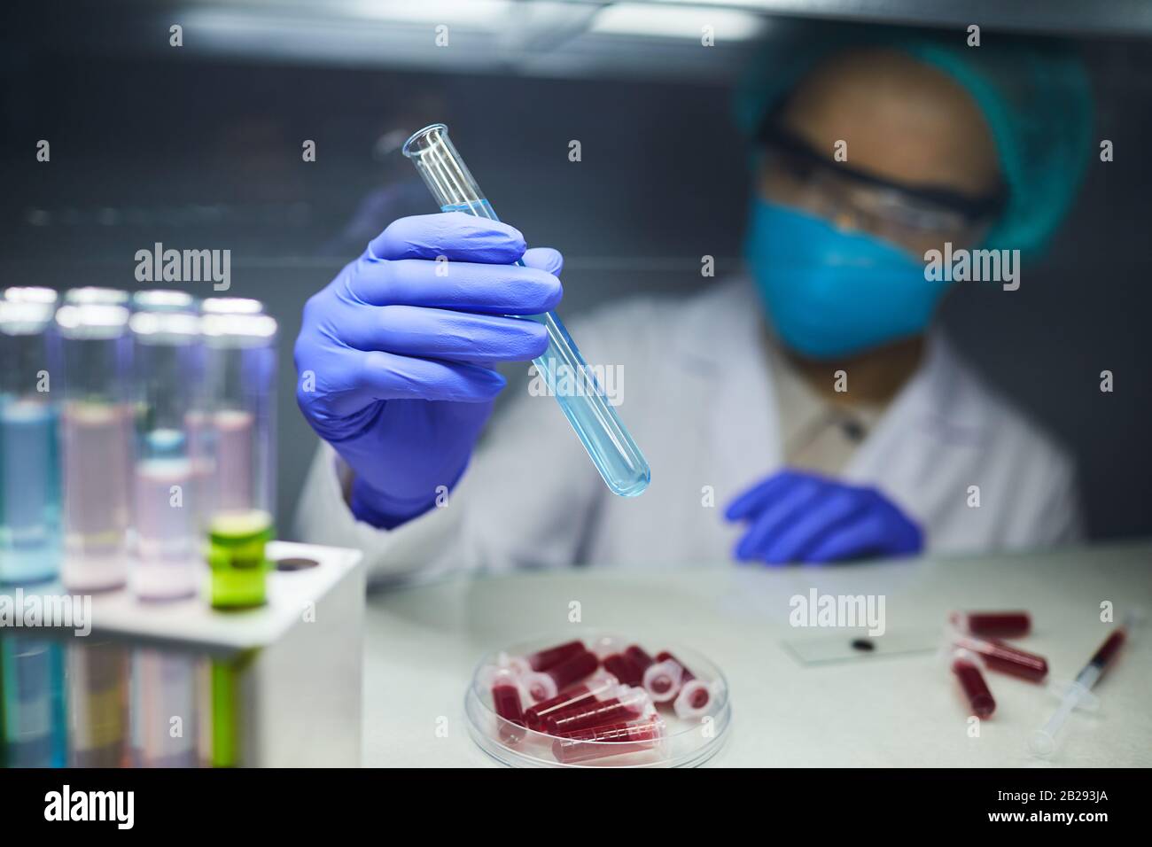 Close up of scientist holding test tube with blue liquid while working ...