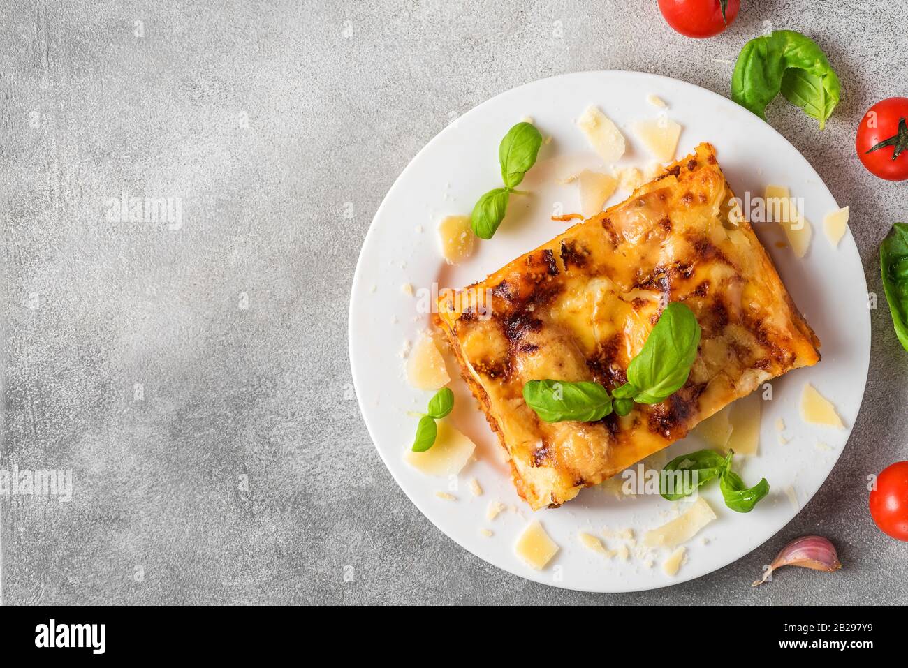 Meat lasagna with fresh basil and parmesan cheese in a plate on gray ...