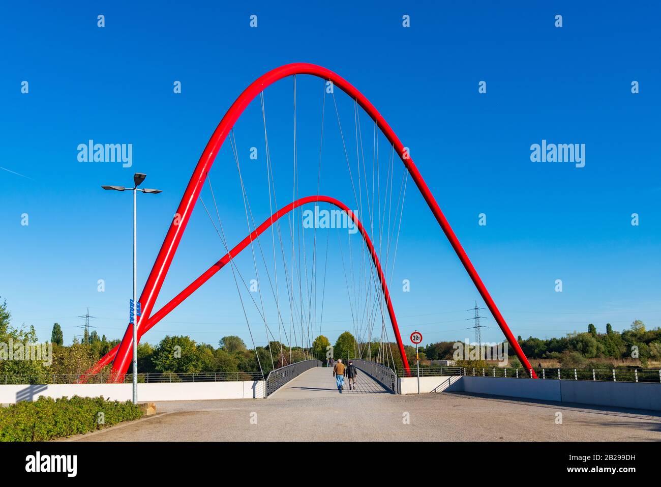 Red bending arch beam structure and people on suspension bridge ...