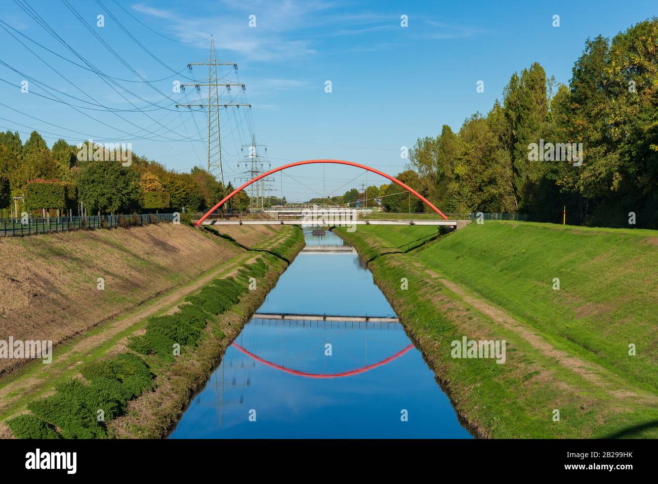 View of canal, embankment, river bank , high voltage posts and red arch ...