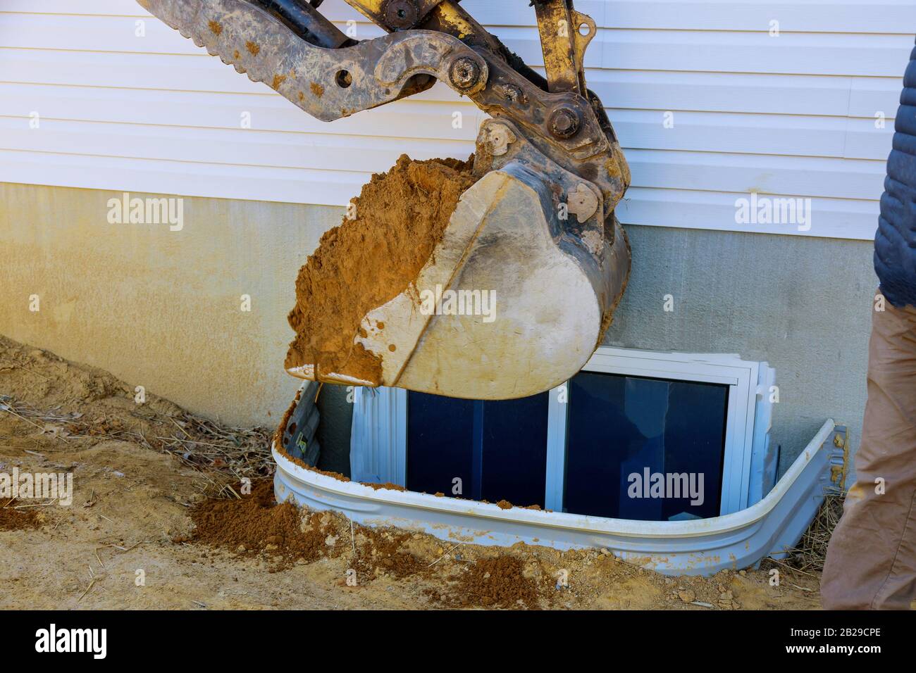 Excavator moving earthmover in the new house under construction window ...