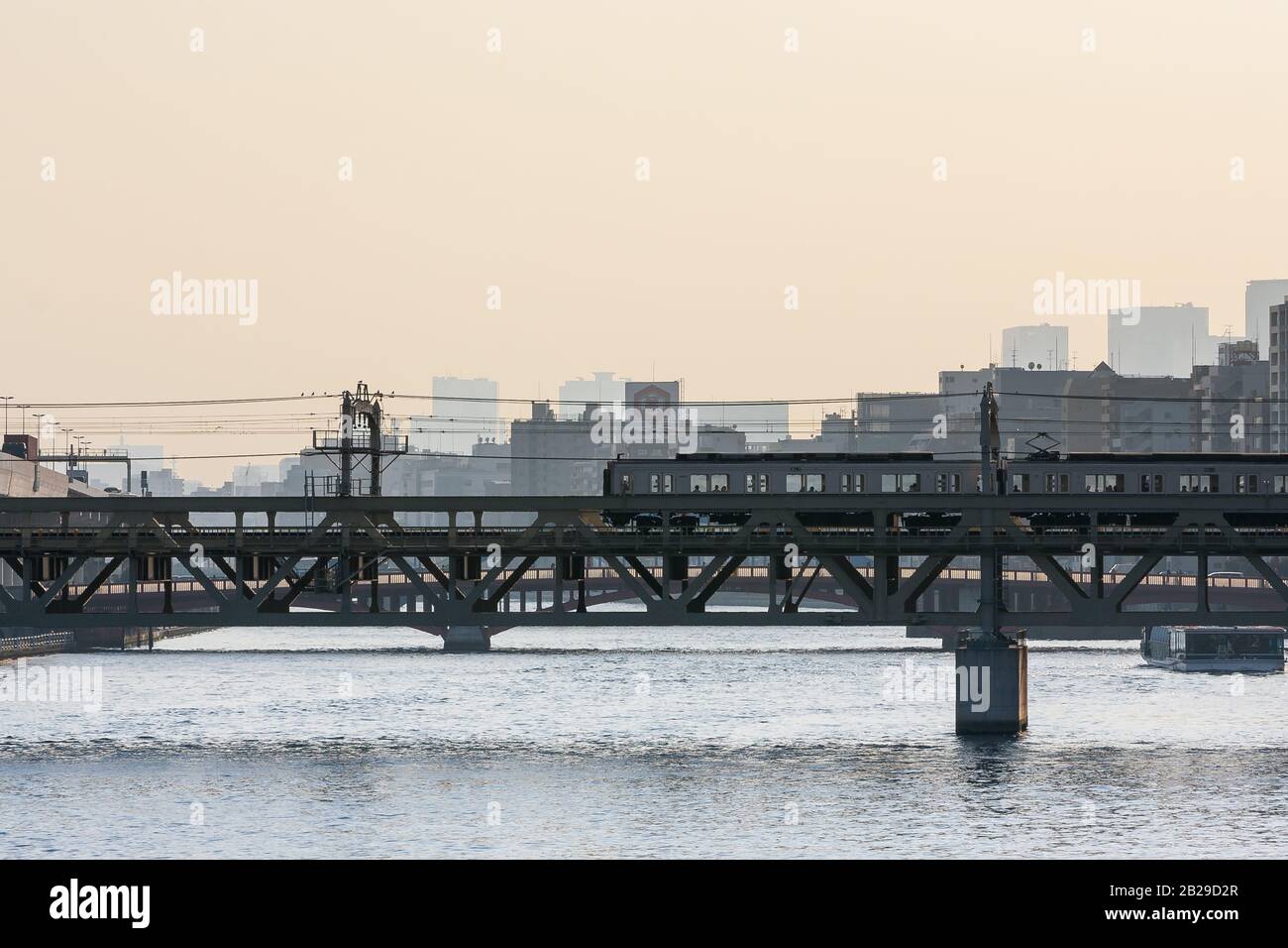 A commuter train cross a rail bridge above the Sumida River, Aasakusa ...