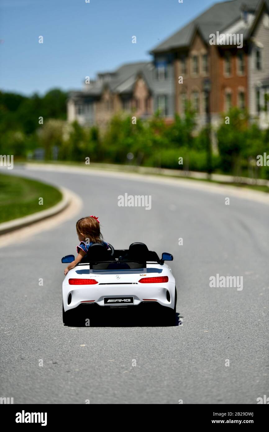 Toddler girl driving her miniature Mercedes-Benz AMG down the street ...