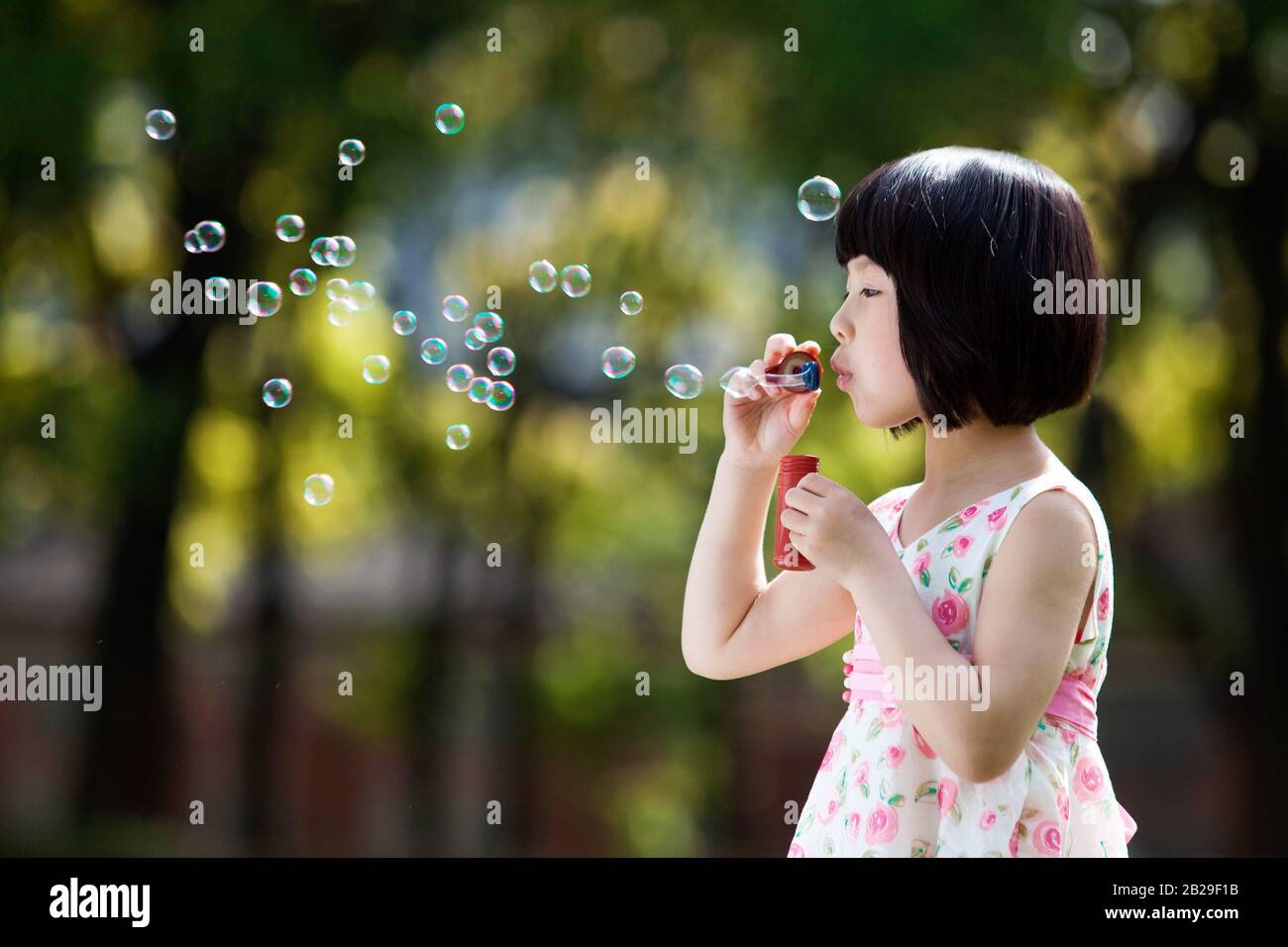 a little asian girl blowing bubbles at park Stock Photo - Alamy