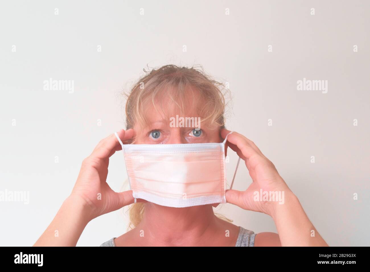 Woman putting on medical mask hi-res stock photography and images - Alamy