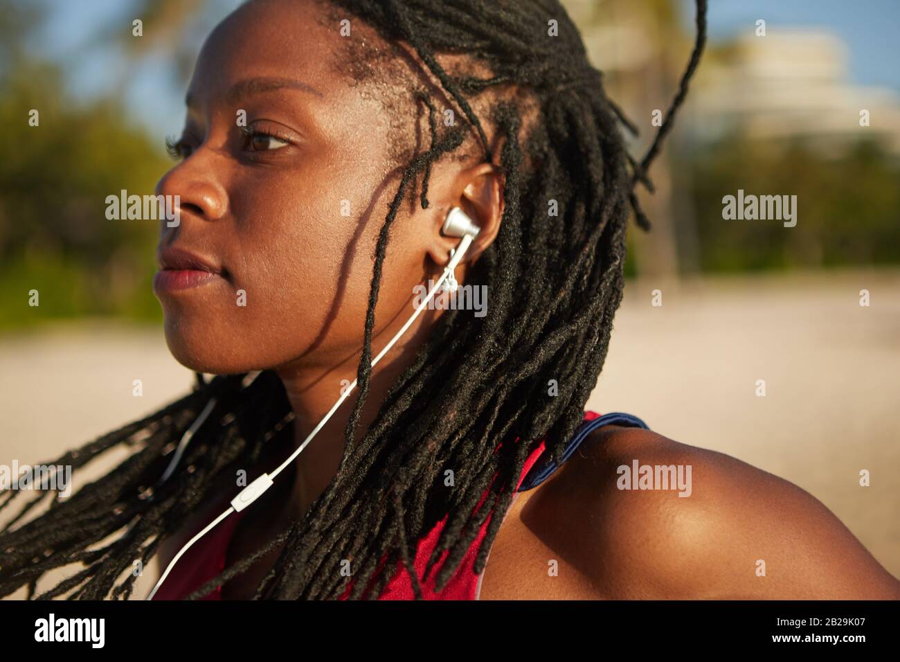 Determined beautiful Black woman with dreadlocks listening to music and ...