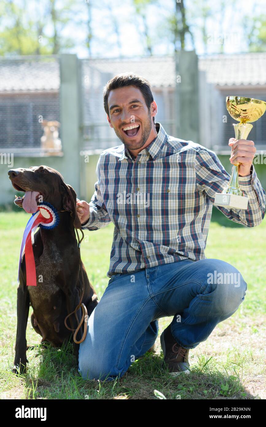 man holding trophy with his dog on the side Stock Photo - Alamy