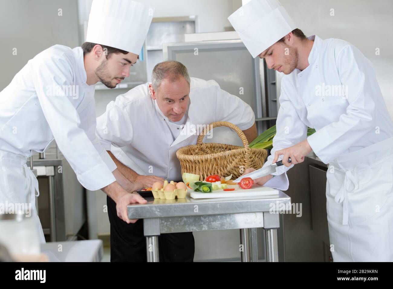 chef with apprentices preparing food in professional kitchen Stock ...