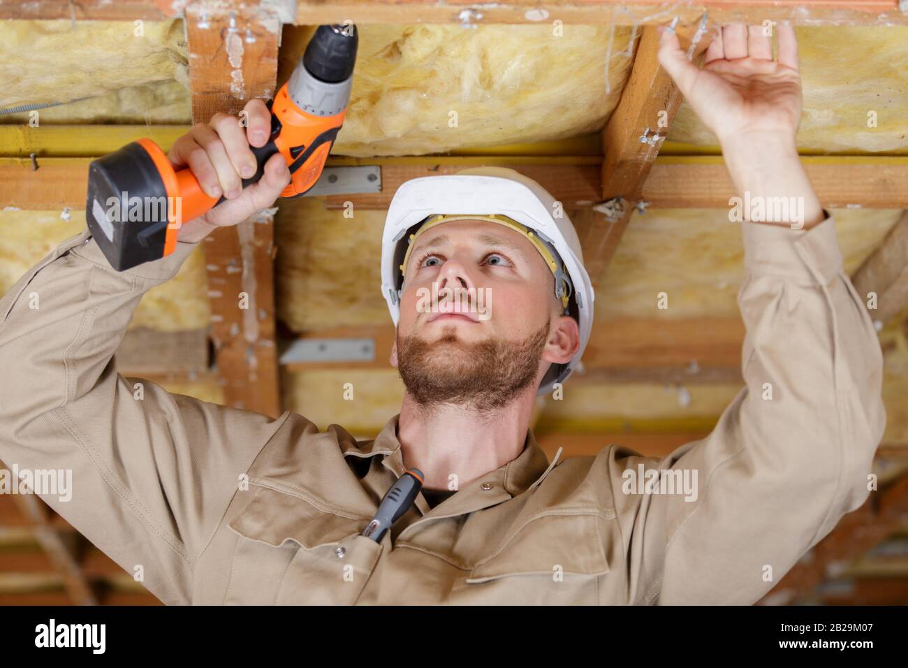 professional male builder using cordless drill on ceiling Stock Photo ...