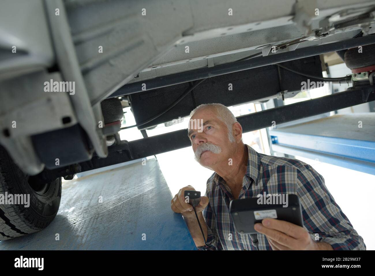 senior professional mechanic fixing under car Stock Photo - Alamy