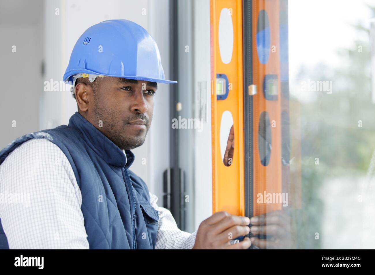 worker is looking at a builders level Stock Photo - Alamy