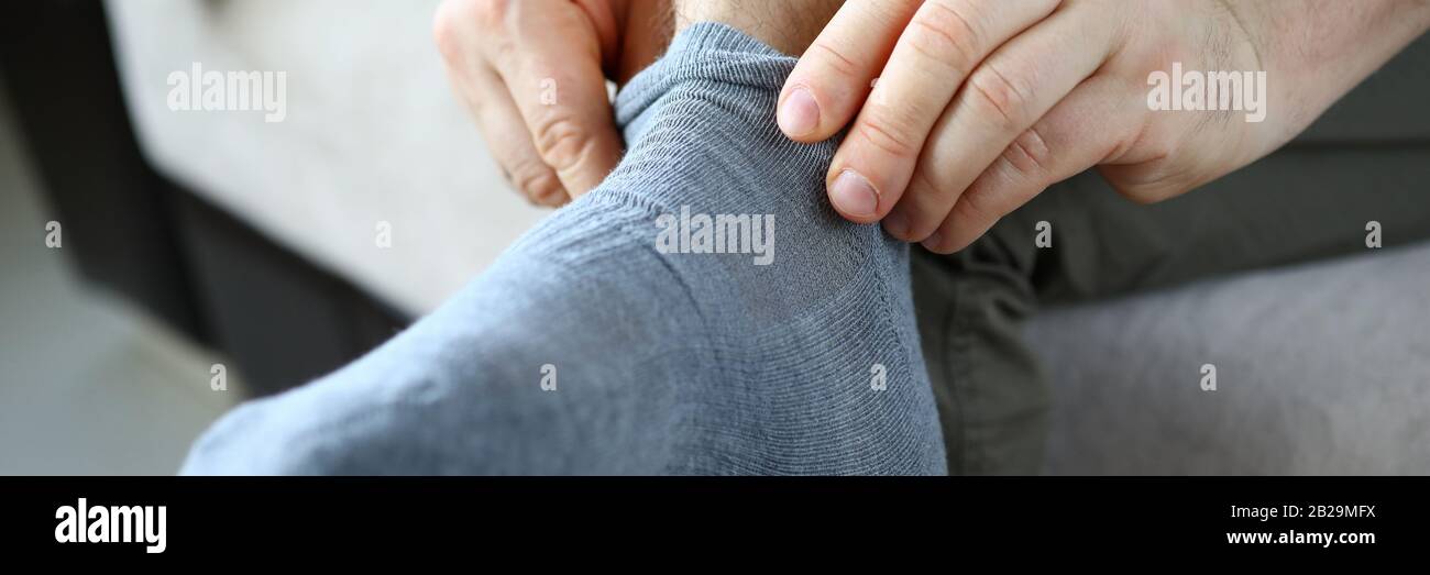 Man at home in morning puts gray socks on his leg Stock Photo - Alamy