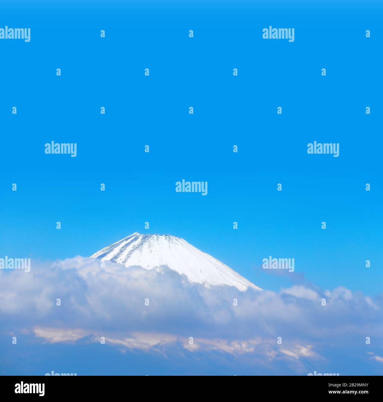 Beautiful sacred Mount Fuji (Fujiyama) in clouds on blue sky background ...