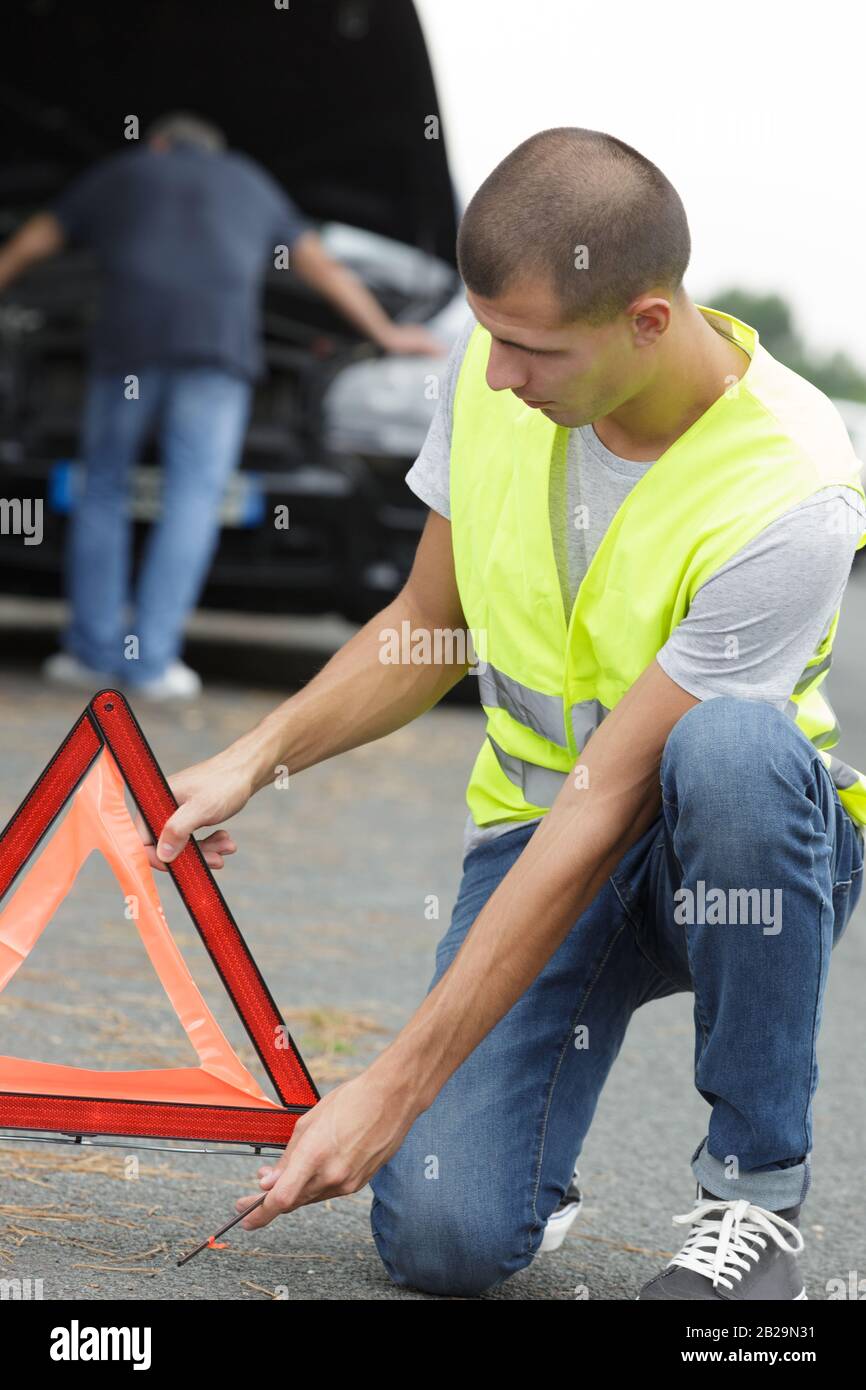 young man putting out his breakdown warning triangle Stock Photo - Alamy