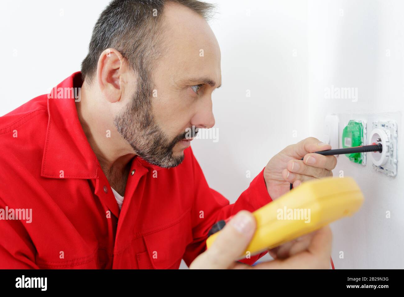 happy electrician checking voltage in electrical wall socket Stock ...