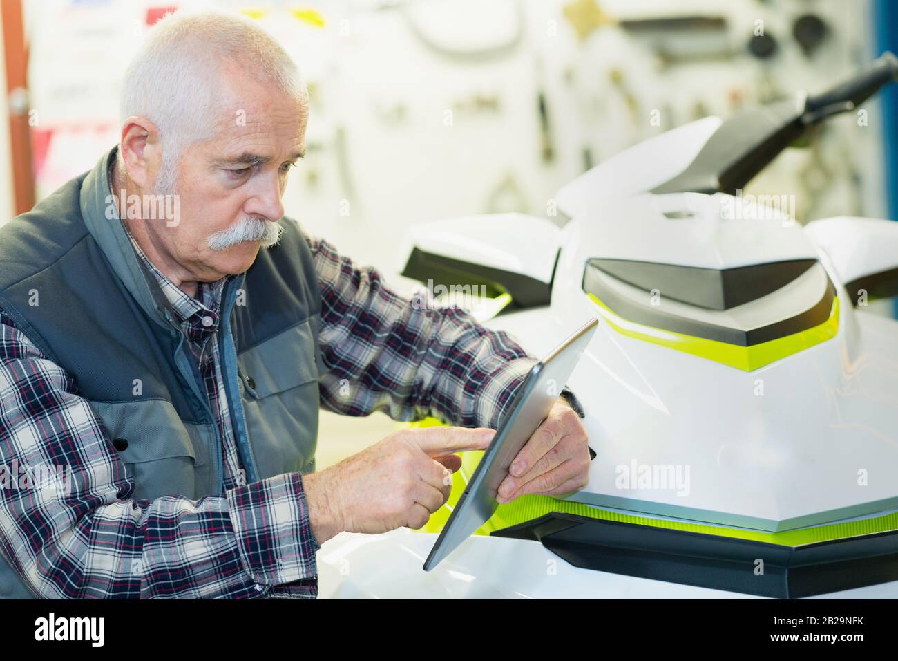 man looking at tablet next to jet ski in store Stock Photo - Alamy