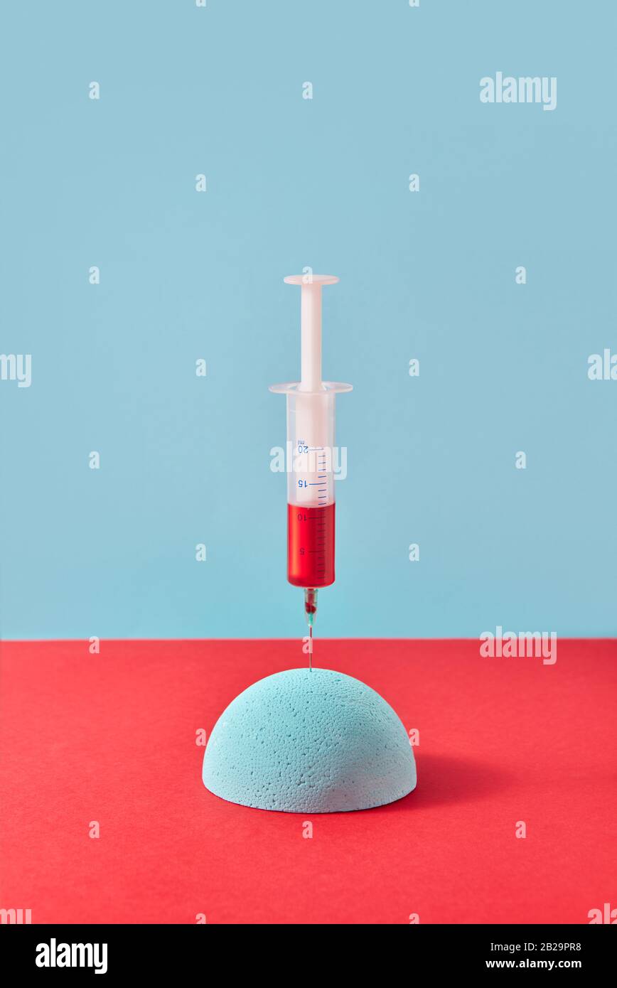 Injection of syringe with red liquid into styrofoam hemisphere Stock ...