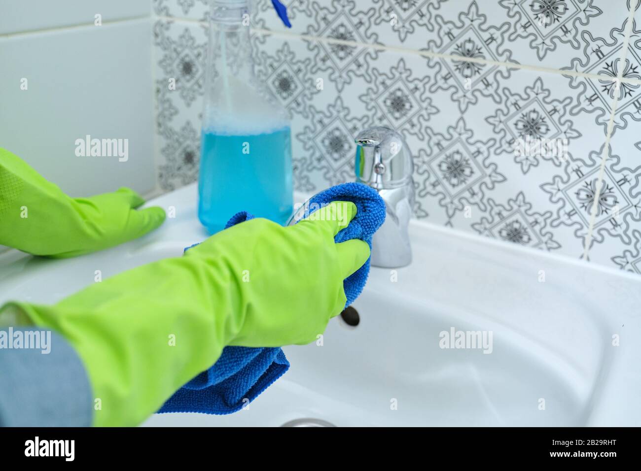 Woman hands cleaning and polishing wash basin and faucet in bathroom ...