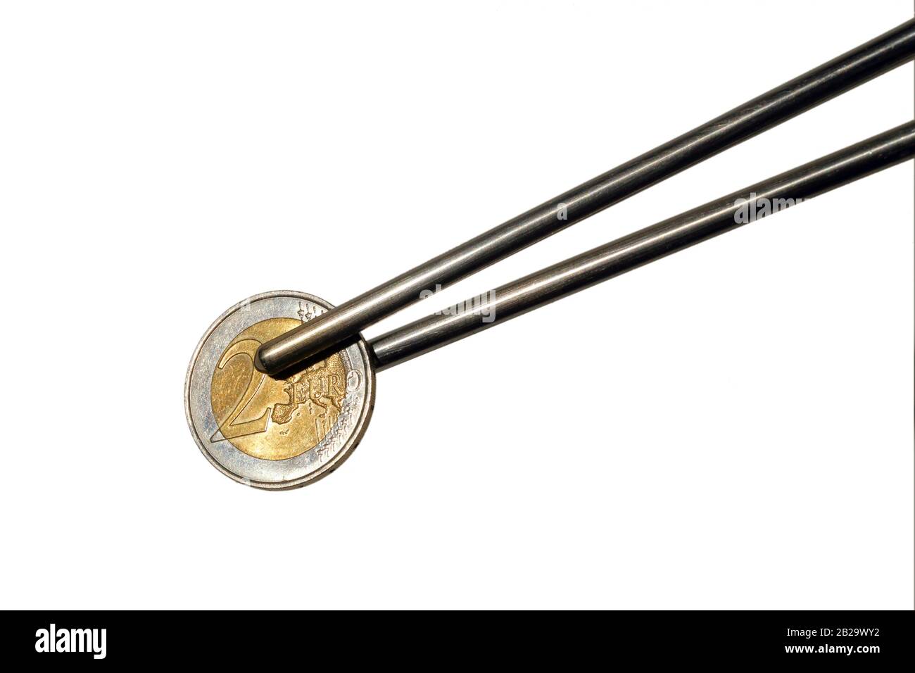 Metal chopsticks holding a Euro coin isolated on a white background ...