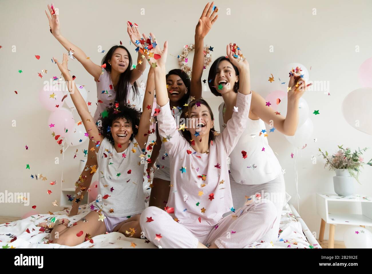 Excited diverse girls throwing confetti, celebrating at party Stock ...