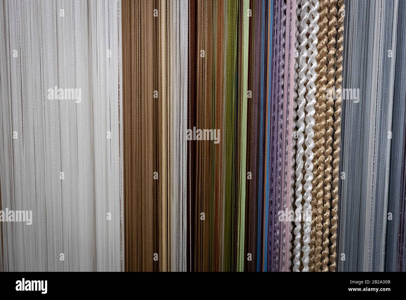 Textile strings and ropes hangs in a fabric shop. Abstract background ...