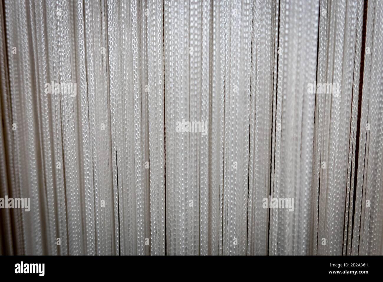 Textile strings and ropes hangs in a fabric shop. Abstract background ...