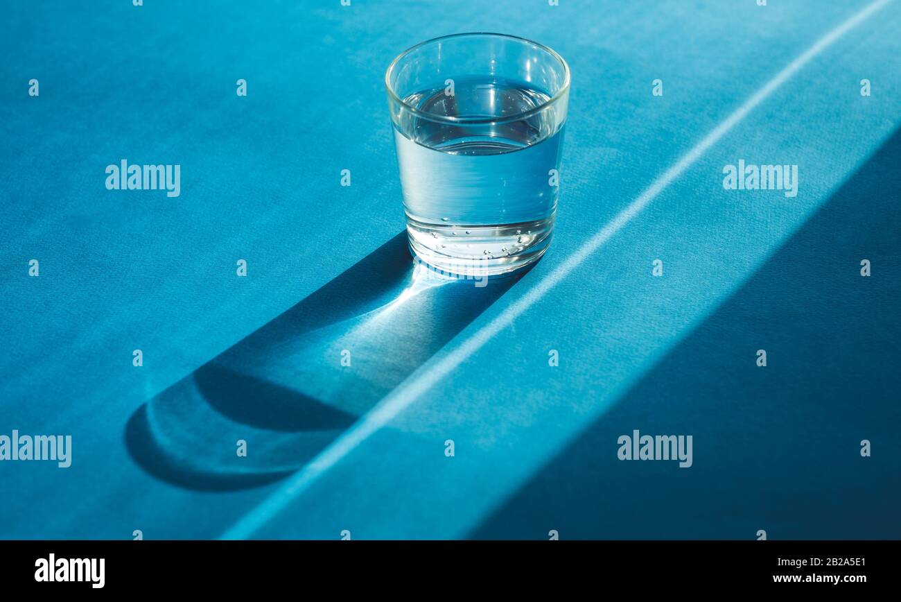 Clear sparkling water into a transparent glass on a blue background ...