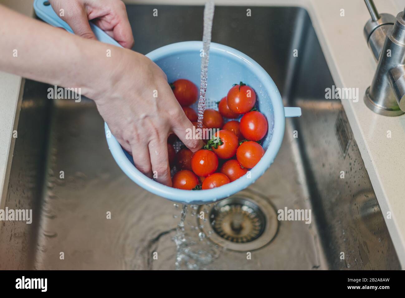 Washing ripe juicy tomatoes in the kitchen for salad Stock Photo - Alamy