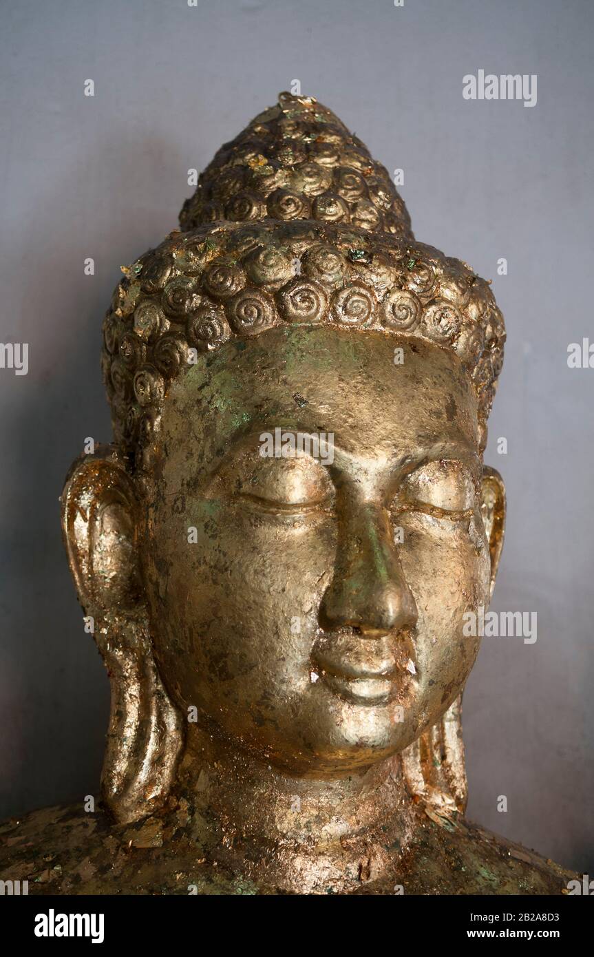 Rounded face of a Buddha meditating with eyes closed with gold leaf ...