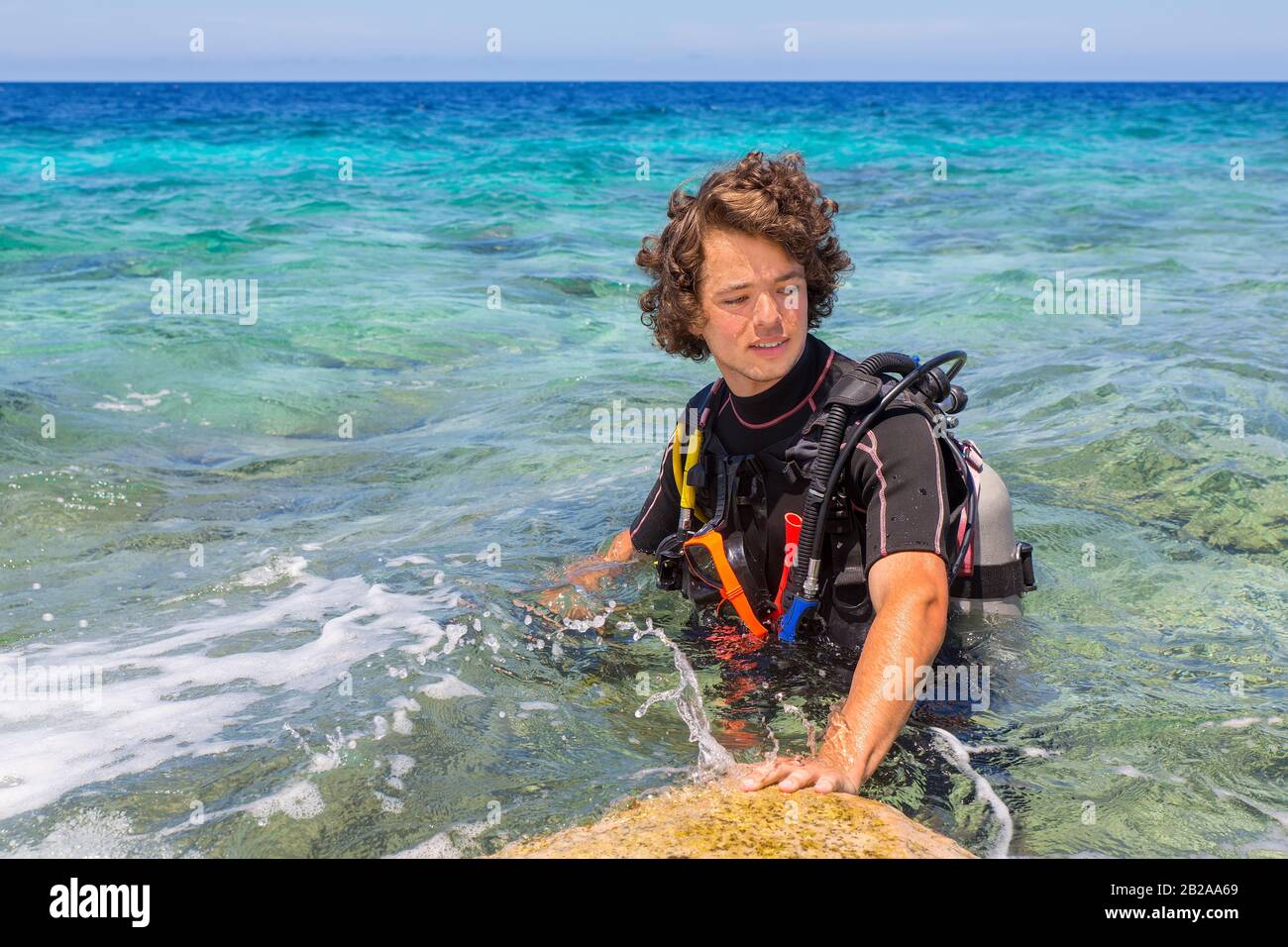 Young european diver stands in blue ocean at coast of island Bonaire ...