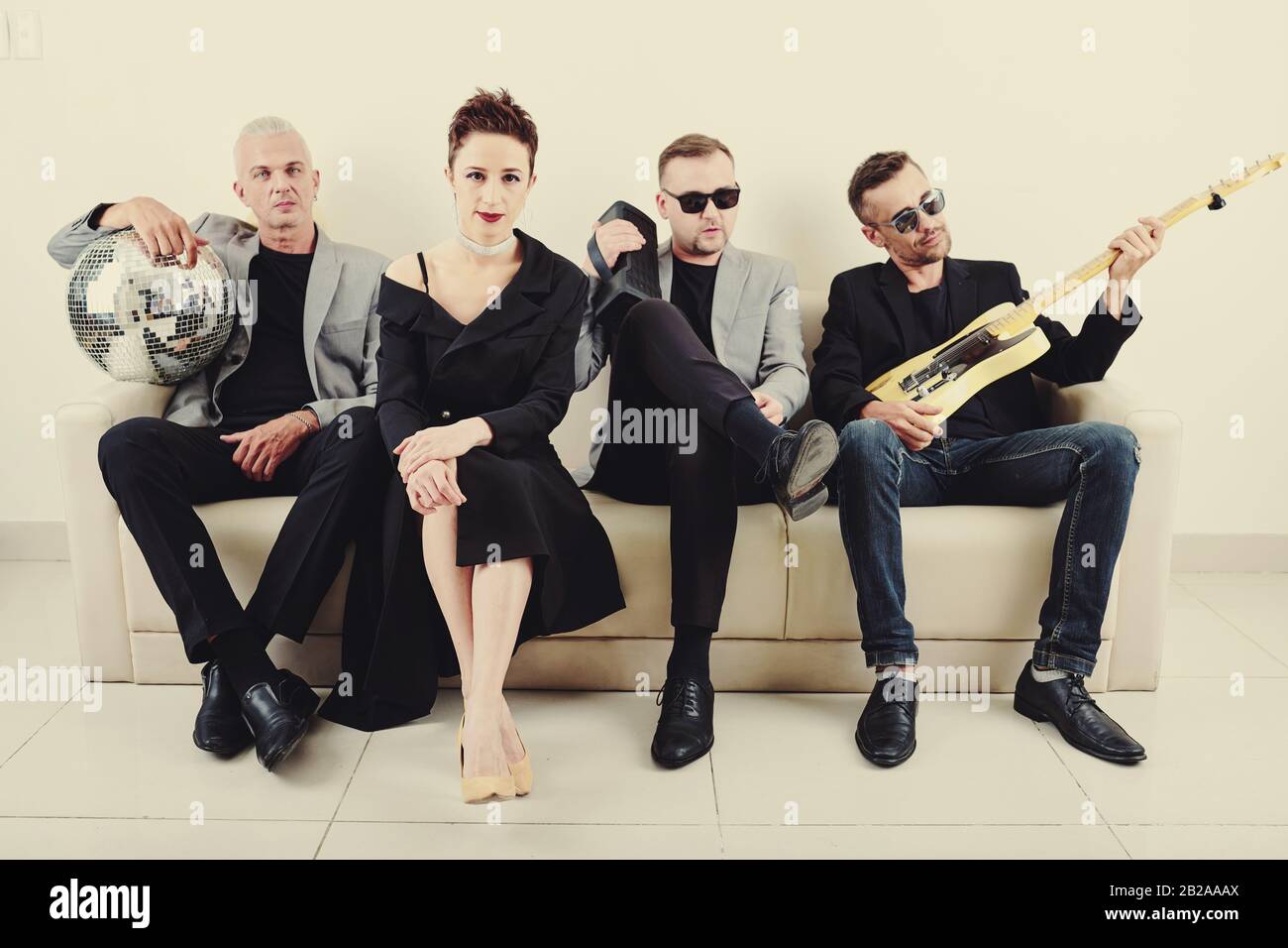 Music band members resting on sofa after concert and listening to music ...