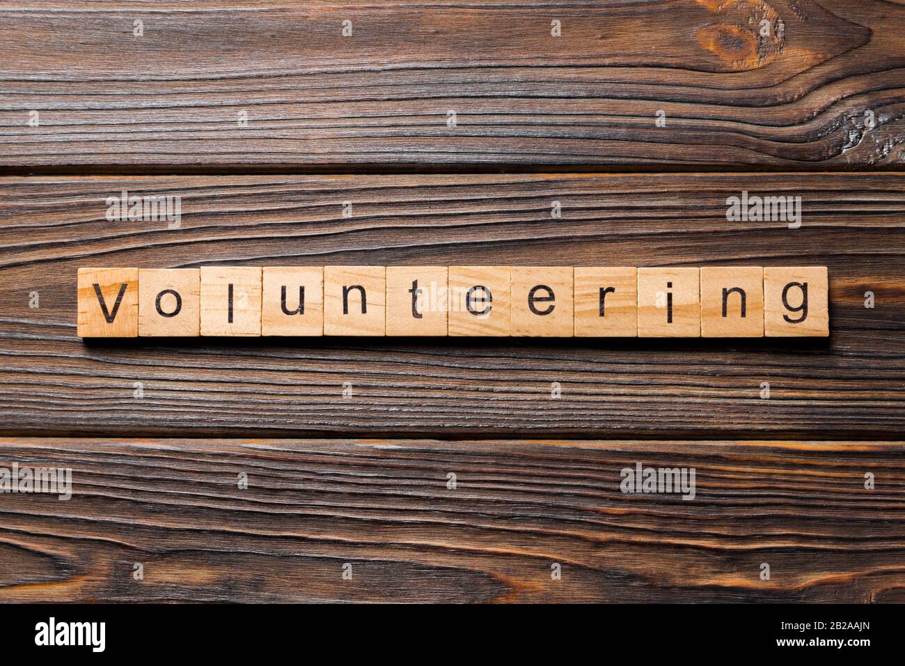 volunteering word written on wood block. volunteering text on table ...