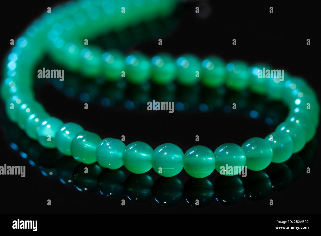 Green nephritis beads isolated on black background Stock Photo - Alamy