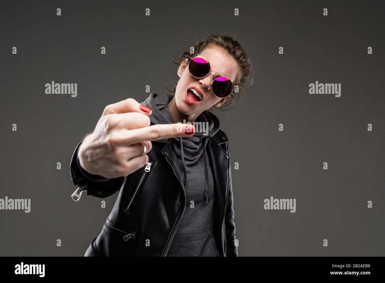 A young girl with rough facial features in a black jacket isolated on ...