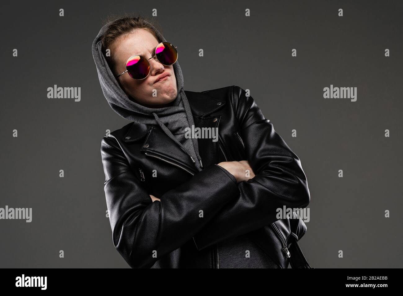 A young girl with rough facial features in a black jacket isolated on ...