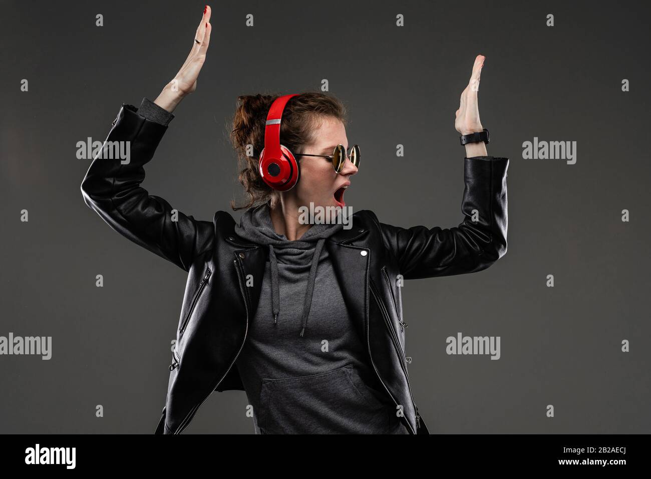 A young girl with rough facial features in a black jacket listens to ...