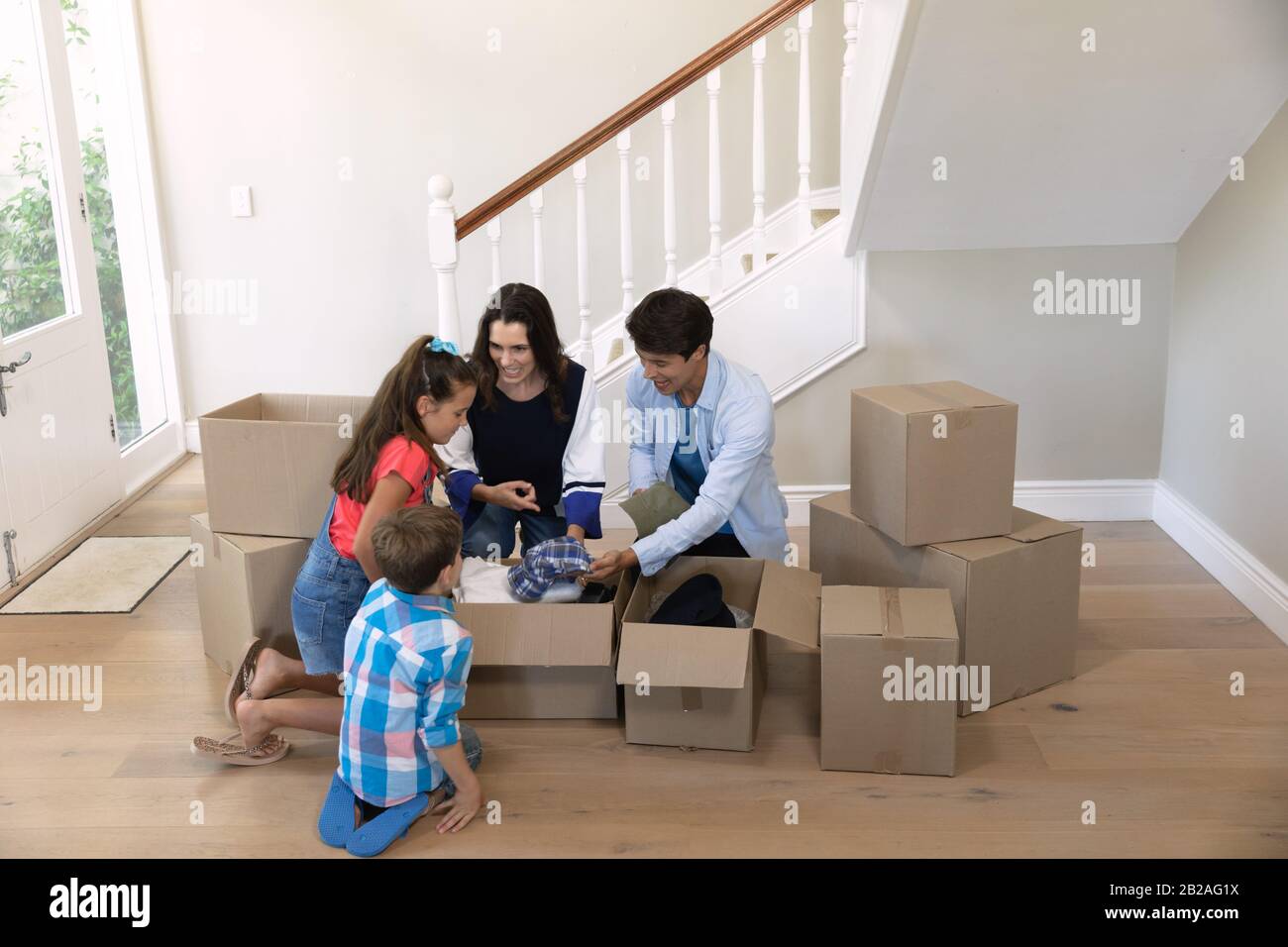 Front view of Caucasian parents with their son and daughter unpacking ...